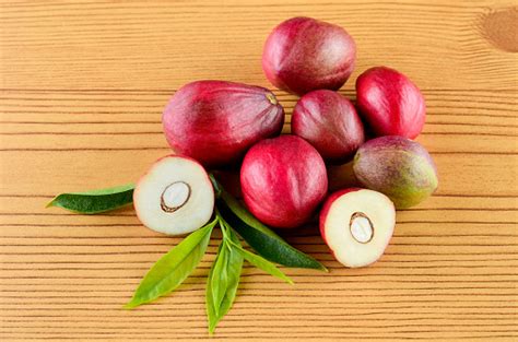 자연 채광과 함께 테이블 위에 돌 박격포 안에 하나님의 왕관 하나님의 왕관 Phaleria 흙 또는 Buah 마 코타 데와 과일