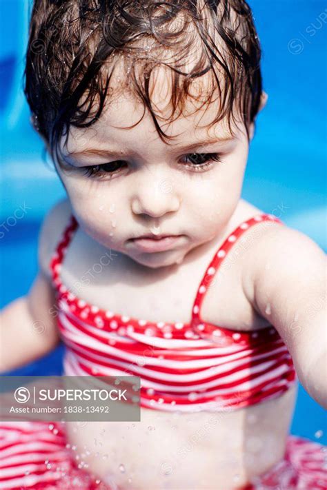 Young Girl In Red Bathing Suit Sitting In Small Pool Close Up Superstock