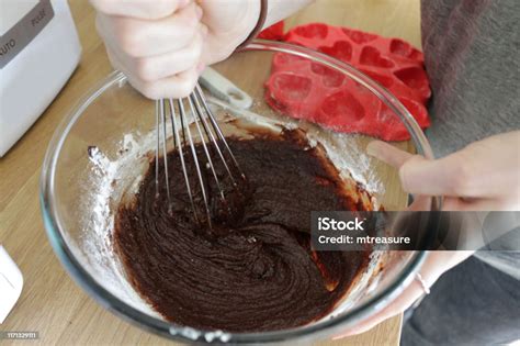 버터 설탕 밀가루 코코아의 홈메이드 초콜릿 빅토리아 스폰지 케이크 반죽 의 이미지 는 나무 부엌 조리대에 유리 부엌 믹싱 그릇에 핸드 헬드 거품기로 혼합되는 날것에 대한