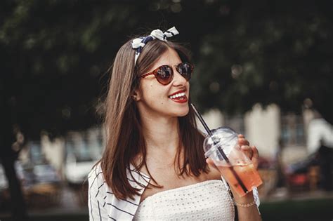 아름 다운 세련 된 젊은 여자 차가운 음료를 들고와 도시 거리에서 행복 한 Hipster 여자 선글라스 레트로 드레스 단일 사용 플라스틱 컵과 빨 대를 들고 개념에 대한