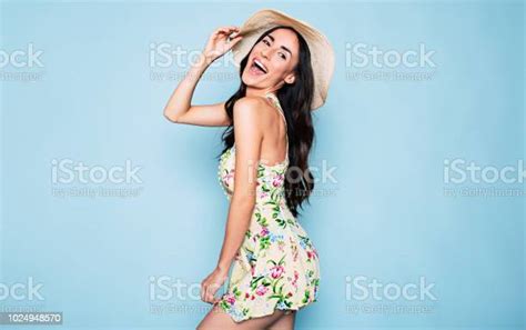 여름 모자와 춤과 파란색 배경 위에 포즈를 취하는 동안 드레스에 아름 다운 세련 되 고 우아한 갈색 머리 여자 드레스에 대한