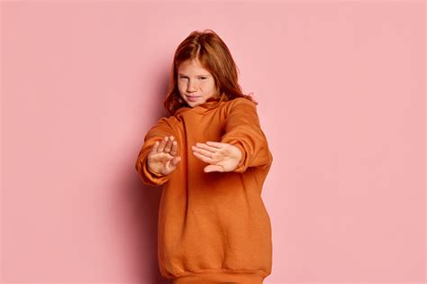 정지 신호 한 겁에 질린 어린 소녀 긴 빨간 머리와 주근깨가 분홍색 배경 위에 고립된 포즈를 취하고 있습니다 어린이 감정의 개념