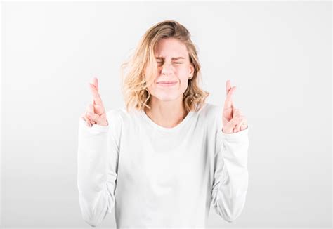 기쁘게 쾌활한 갈색 머리 여자는 행운을 기원에 모든 노력을 두고 손가락을 교차 더 나은에 대한 믿음을 가지고 흰색 배경에 고립
