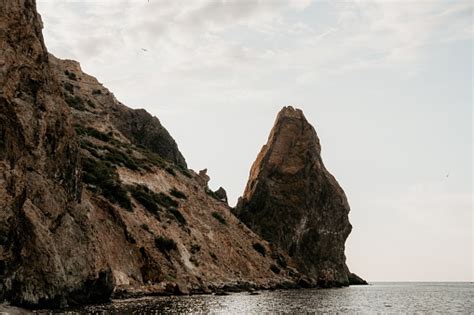 일몰 동안 해변을 둘러싼 평화로운 바다 경관 바위 화산 절벽은 따뜻한 일몰에 의해 조명된다 맑은 하늘 구름없음 아무도 공간을 복사합니다 평온한 침묵과 자연과의 단합의 개념