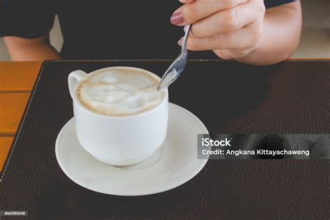 여자 손 커피 숟가락 들고와 빈티지 스타일에서 카페 나무 테이블에 흰 머그잔에 뜨거운 커피를 저 어 갈색에 대한 스톡 사진 및