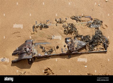 A Large Metal Object Rusting On The Beach Half Buried In Sand