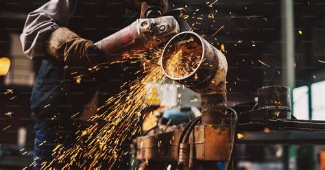 산업 작업장에서 전기 그라인더가 있는 작업 테이블에 금속 파이프를 절단하는 보호 유니폼 직물 작업자 사진 Unsplash의 세르비아 이미지