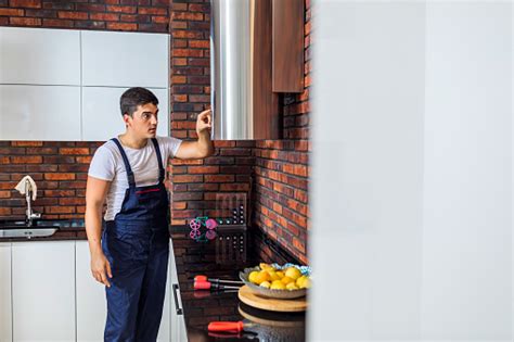 Male Electrician With Clipboard Repairing Kitchen Extractor Filter