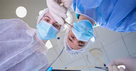 남성 외과 의사는 손에 특수 수술 바늘을 들고 있고 여성 조수는 근처에 있습니다 사진 Unsplash의 수술용 조명 이미지