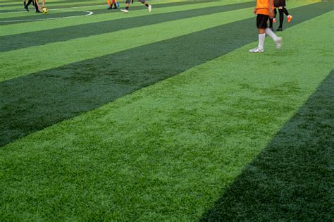 경기 중 선수들의 다리가 움직이고 있는 녹색 축구장의 낮은 각도에서 본 모습입니다 생동감 넘치는 인조 잔디는 경기의 에너지와