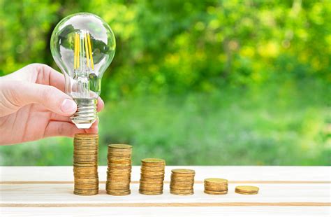 비즈니스 개념 녹색 보케 배경이 있는 나무 탁자 위에 동전 위에 램프를 들고 있는 손 새로운 아이디어와 창의성 비즈니스 아이디어 비즈니스 성공 회복 과 비즈니스 성장 공간을