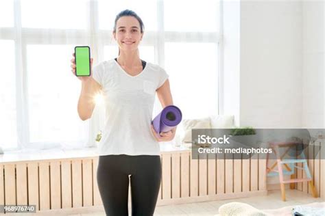 졸리 요가 운동으로 멋진 애플 리 케이 션을 추천 하는 동안 스마트폰 화면 및 지주 압 연 지도 보여주는 아름 다운 젊은 여자를 기쁘게 건강한 생활방식에 대한 스톡 사진 및