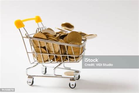 흰색 배경에 고립 된 그것에 떨어지는 황금 동전과 노란색 플라스틱 손잡이 가진 쇼핑 슈퍼마켓 식료품 푸시 카트 닫습니다 돈의
