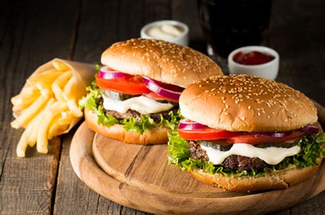클로즈업 사진 쇠고기 양파 토마토 양상추 치즈와 향신료로 만든 맥주와 햄버거 감자 튀김 및 칩 나무 소박한 테이블에 신선한