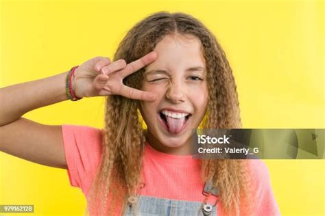 행복 한 십 대 소녀 한순간 혀를 보여주는 취재 한 눈 밝은 노란색 스튜디오 배경 십대 소녀에 대한 스톡 사진 및 기타 이미지 십대 소녀 한 사람 12 13세