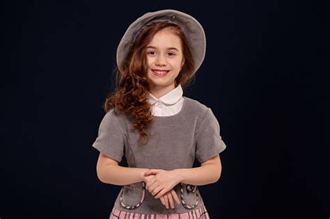 검은 배경에 포즈를 취하는 길고 곱슬 머리로 사랑스러운 어린 아이의 스튜디오 샷 갈색 머리에 대한 스톡 사진 및 기타 이미지