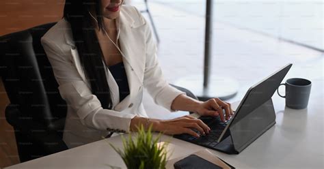 이어폰을 통해 음악을 듣고 사무실에서 컴퓨터 태블릿으로 작업하는 사업가의 잘린 샷 사진 Unsplash의 사업 이미지