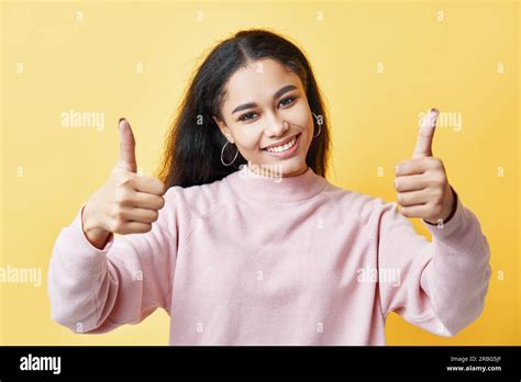 Smiling Pretty Woman Showing Thumb Up Sign Over Yellow Background