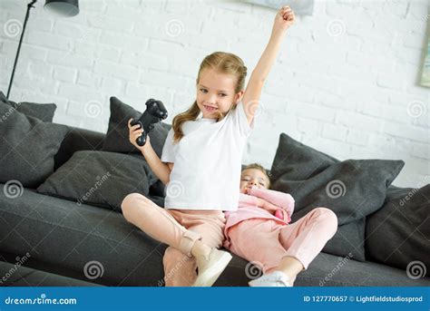 Cute Little Sisters With Gamepads Playing Video Game Together Stock