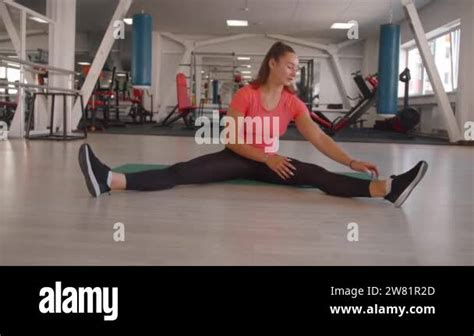 A Young Girl Works Out In The Gym And Does Stretching While Sitting On