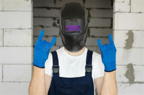 Male Construction Worker Wearing A Welding Helmet And Blue Gloves