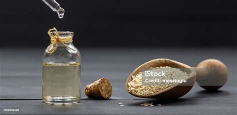 Botol Kaca Minyak Wijen Dan Biji Wijen Mentah Dalam Sekop Kayu Di Atas