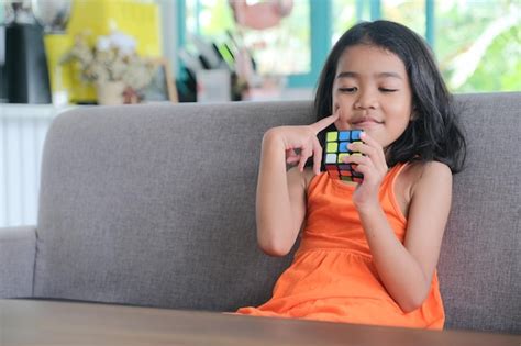 Niña Sentada Sola En El Sofá Jugando Cubos De Rubik Foto Premium