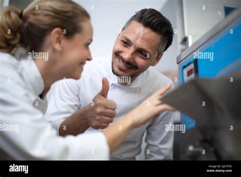 Baker Instructing Apprentice How To Knead Dough Properly Stock Photo