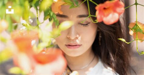 머리에 꽃을 꽂은 채 나무 아래에 서 있는 여자 사진 Unsplash의 무료 사진술 이미지