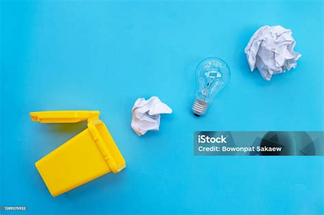 Tempat Sampah Kuning Dengan Bola Lampu Dan Kertas Kusut Putih Di Latar