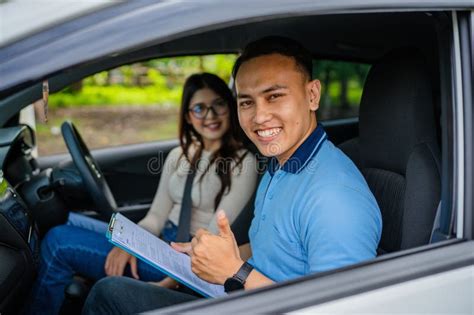 Young Couple Enjoying A Lesson In A Car While Smiling And Giving A