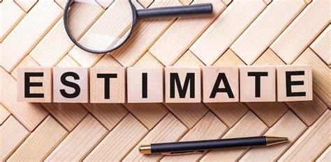 Estimate라는 단어가 있는 나무 큐브는 돋보기와 펜 사이의 나무 배경에 서 있습니다 프리미엄 사진