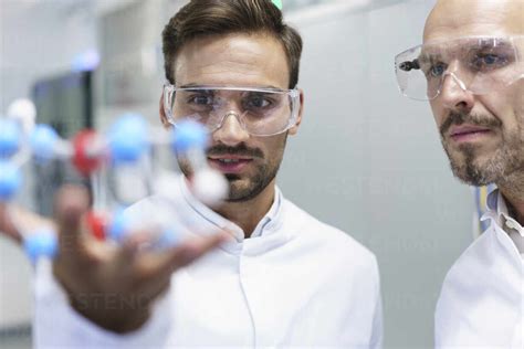 Confident Male Scientists Analyzing Molecular Structure At Illuminated
