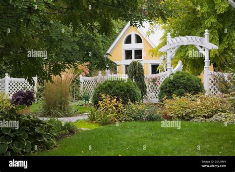 White Wooden Arbour With Entrance Gate And Lattice Fence In Front Yard