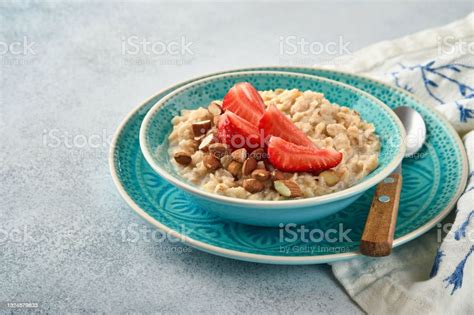 딸기 슬라이스 견과류 아몬드 꿀을 회색 테이블에 파란색 그릇에 넣은 오트밀 죽 건강한 식습관 다이어트 채식주의 음식 컨셉 텍스트