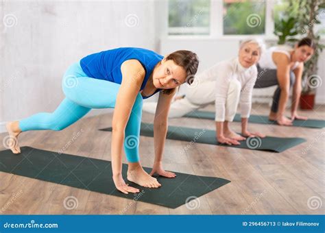 Diligent Women Practicing Lizard Pose Of Yoga In Light Fitness Room