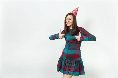 꽤 백인 젊은 여 자가 격자 무늬 드레스와 매력적인 미소로 생일 파티 모자 휴일 표시를 축 하 하는 광고에 대 한 흰색 배경 위에 고립 된 두 손 복사 공간에 최대 엄지