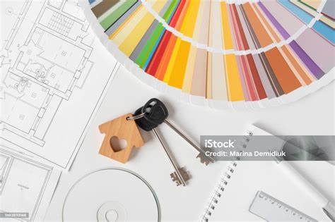 색상 가이드에서 인테리어 디자인의 색상을 선택하는 손 아파트 스케치 페인트 팔레트 집 모델 및 배경에 열쇠 고리 컬러 견본을 사용하는 건축가 블루프린트가 있는 하우스 플랜