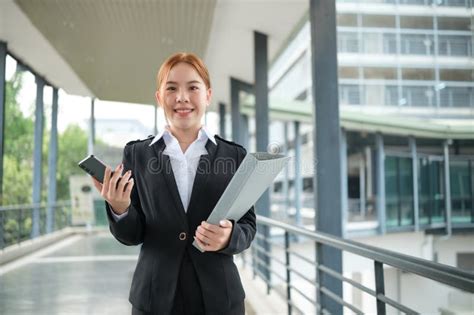 A Young Asian Businesswoman Wearing A Suit Holding Files Standing On