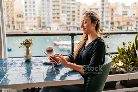 몰타의 세인트 줄리안 베이에 있는 테라스에 있는 카페에서 태블릿을 사용하는 젊은 여성 바다에 대한 스톡 사진 및 기타 이미지