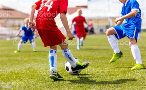 빨간색과 파란색 축구 셔츠를 입은 청소년 주니어 운동 선수 스포츠 교육 축구 경기장에서 공을 차는 어린이 축구 선수 스포츠 축구