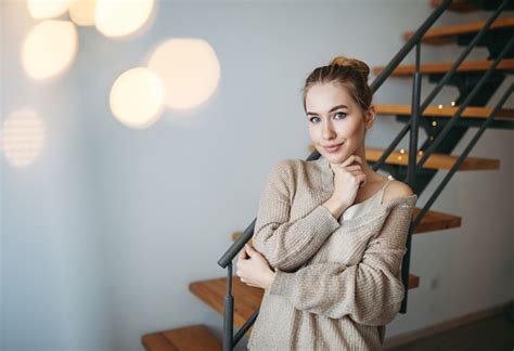 젊은 아름 다운 미소 소녀 와 금발 머리 에 저녁 베이지 색 실크 드레스 와 아늑한 가디건 앞 의 계단 에 집 가정 생활에 대한