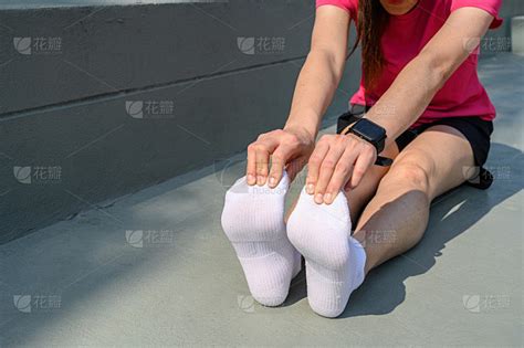 女跑步者试图做足部伸展运动以防止受伤。
