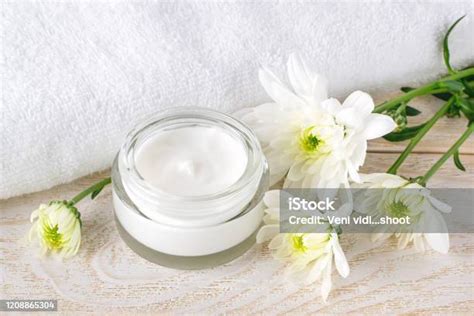 신선한 국화 싹 옆에 오픈 유리 항아리에 얼굴 크림과 흰색 나무 표면에 흰색 테리 수건 뷰티 스킨케어 화장품 컨셉 0명에 대한