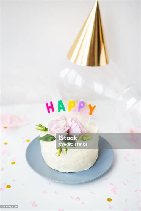 과자의 배경에 신선한 Eustoma 꽃으로 장식 된 매우 아름다운 작은 흰색 케이크와 생일 축하 비문 풍선 모자 휴일 개념입니다