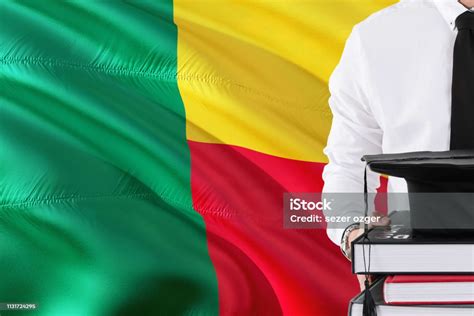 성공적인 Beninese 학생 교육 컨셉 베냉 국기 배경 위에 책과 졸업 모자를 들고 교사 교육 관련 직업에 대한 스톡 사진 및