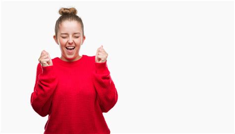 무기와 성공에 대 한 흥분된 롤빵과 빨간 스웨터를 입고 젊은 금발의 여 자가 축 하 승리 미소 발생 합니다 우승자 개념입니다 겨울에 대한 스톡 사진 및 기타 이미지 Istock