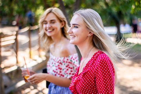 Two Attractive Blonde Girlfriends Talking And Hugging In The Park