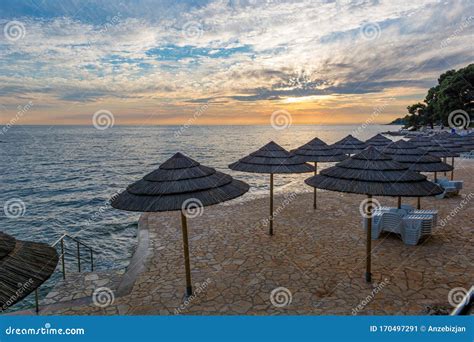Ocean Sunrise With Grass Umbrellas Waiting For Early Guests Stock