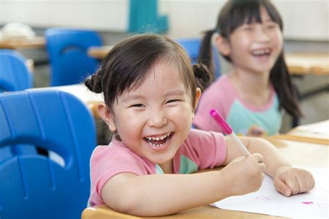快乐的小女孩在教室里的桌子上写东西 包图企业站